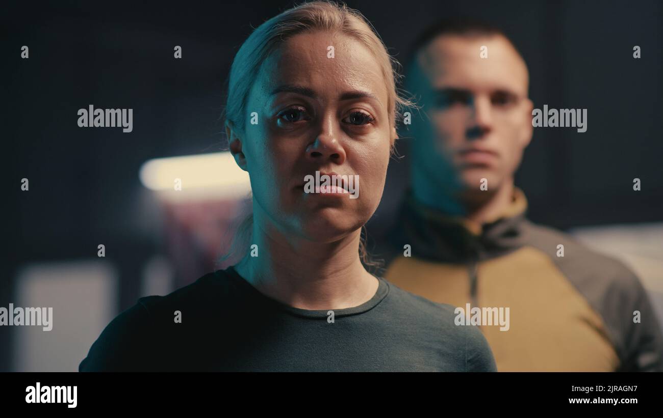Male and female athletes looking at camera with serious faces in dark ...