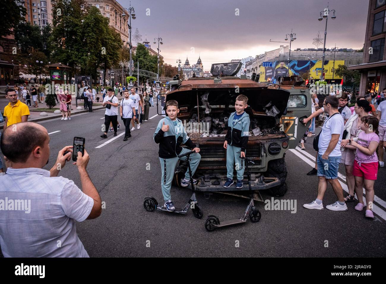 A father takes photos of his sons standing next to a destroyed Russian ...