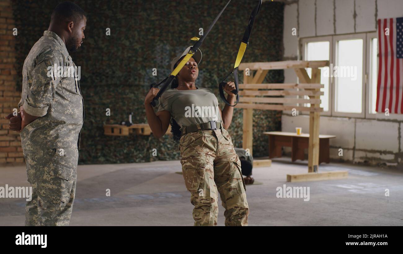 African American military woman doing exercise with training ropes and ...