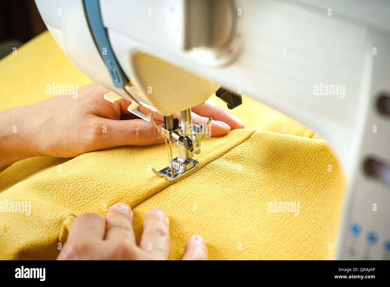 Seamstress female hands holding and stitching yellow textile fabric on ...