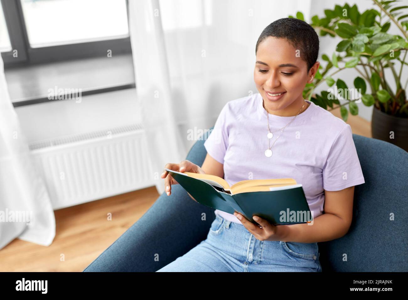 happy african american woman reading book at home Stock Photo - Alamy