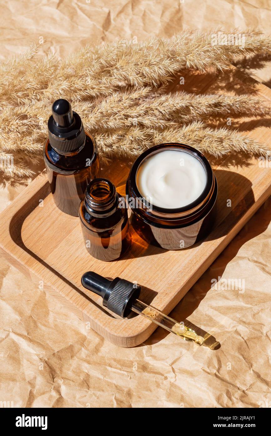Set of amber glass cosmetic bottles on wooden tray. dropper bottle and ...