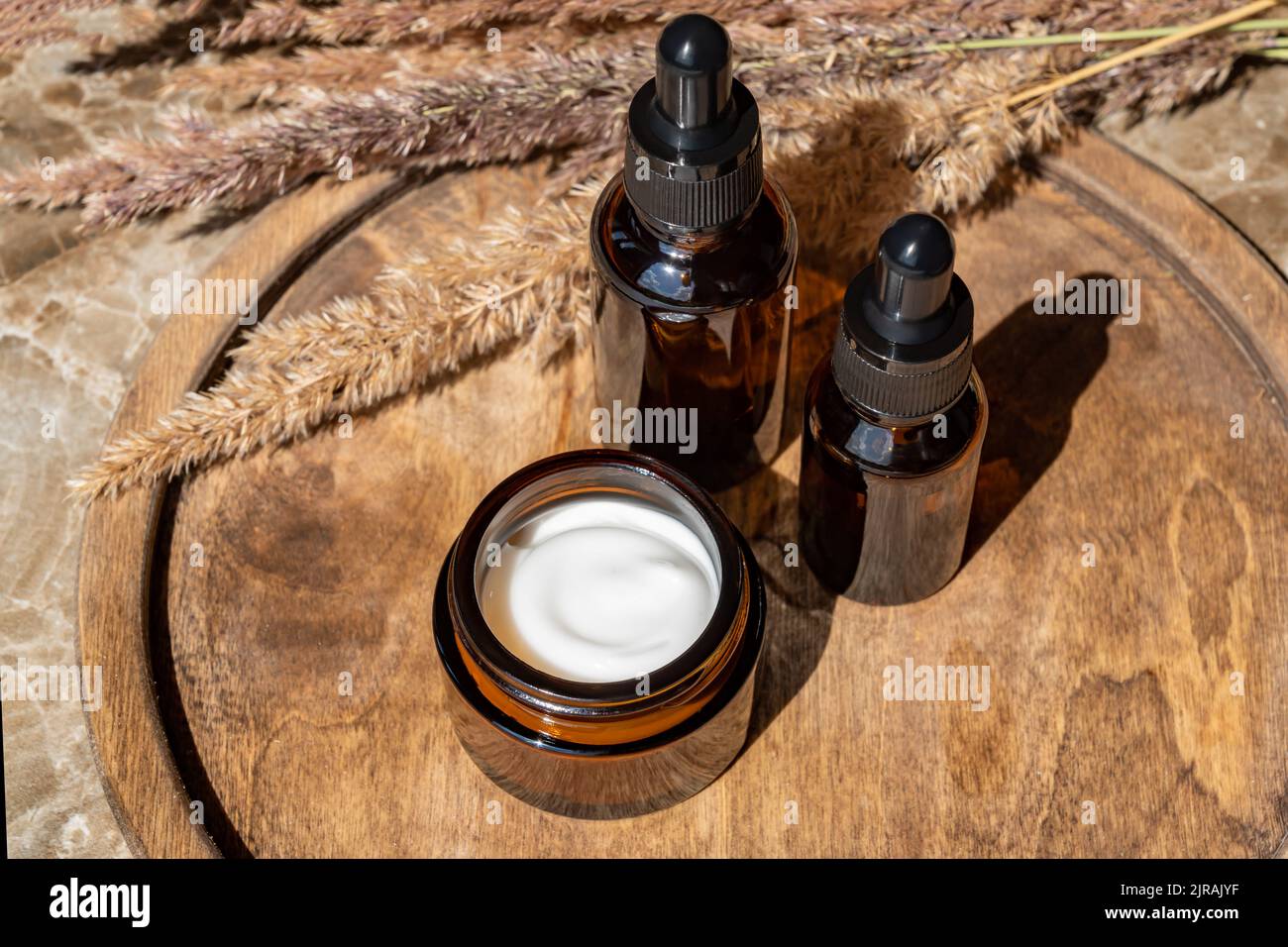 Set of amber glass cosmetic bottles on wooden tray. dropper bottle and ...