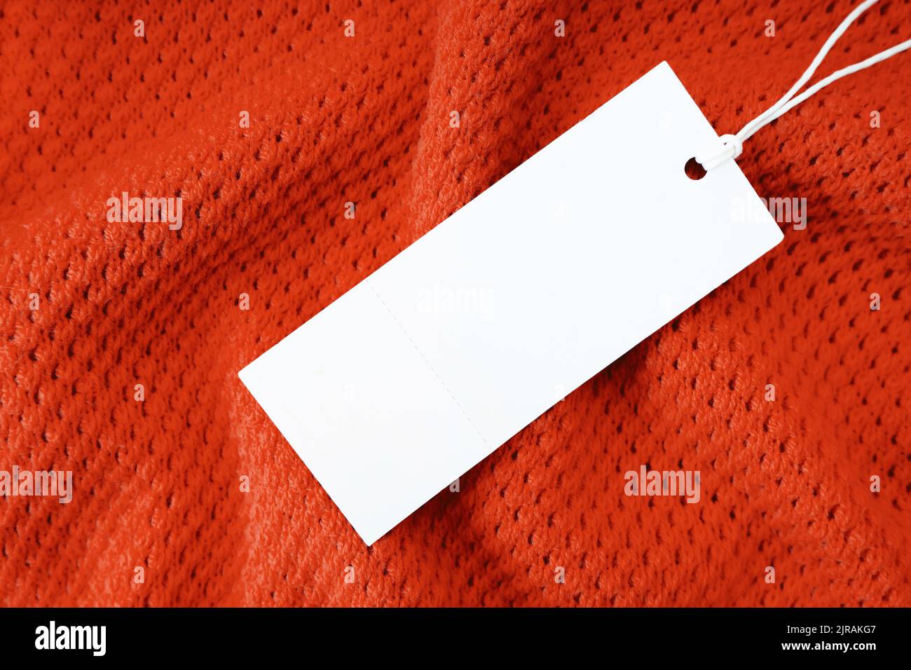 White blank rectangular clothing tag, label mockup template on red ...