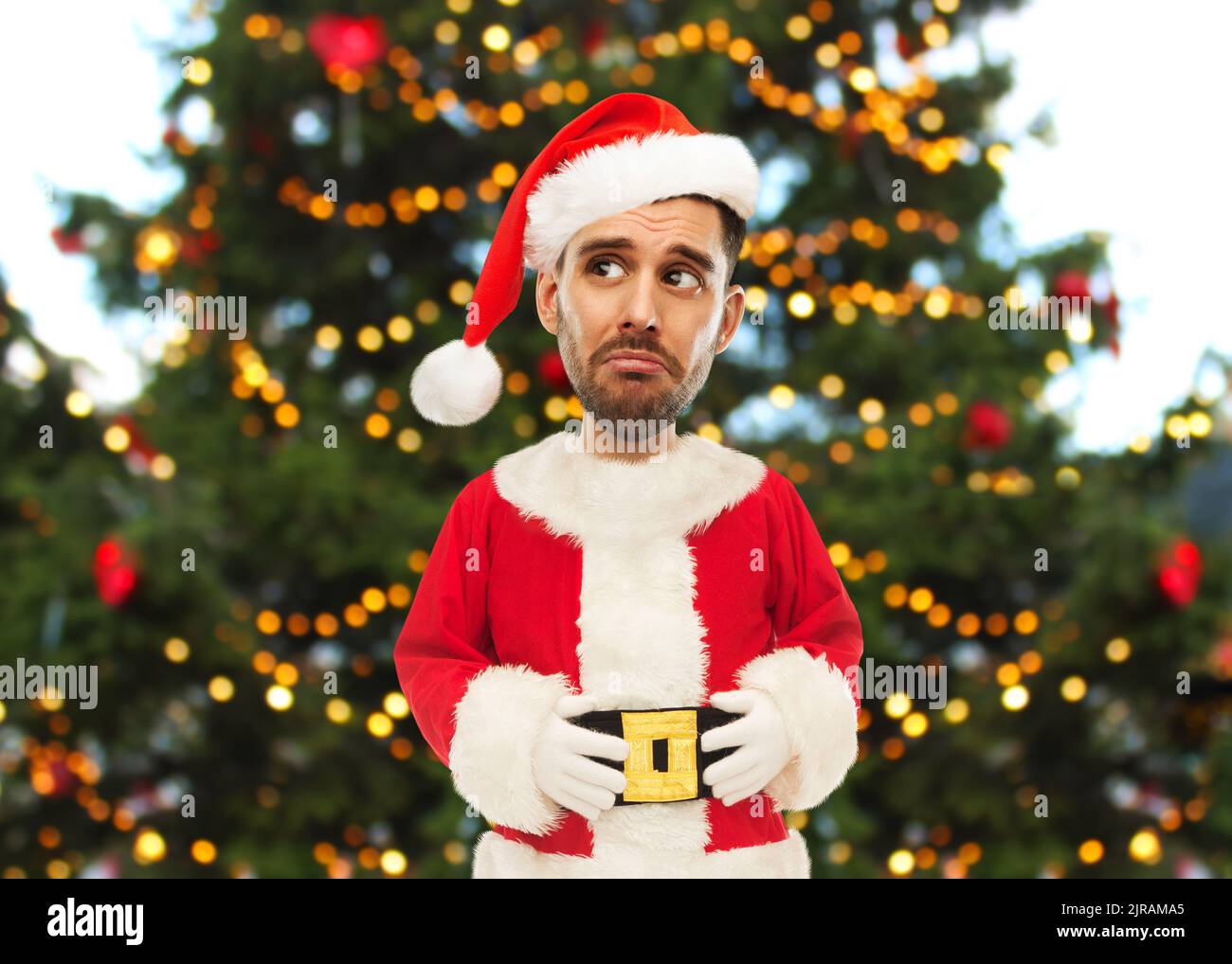 sad man in santa claus costume over christmas tree Stock Photo - Alamy