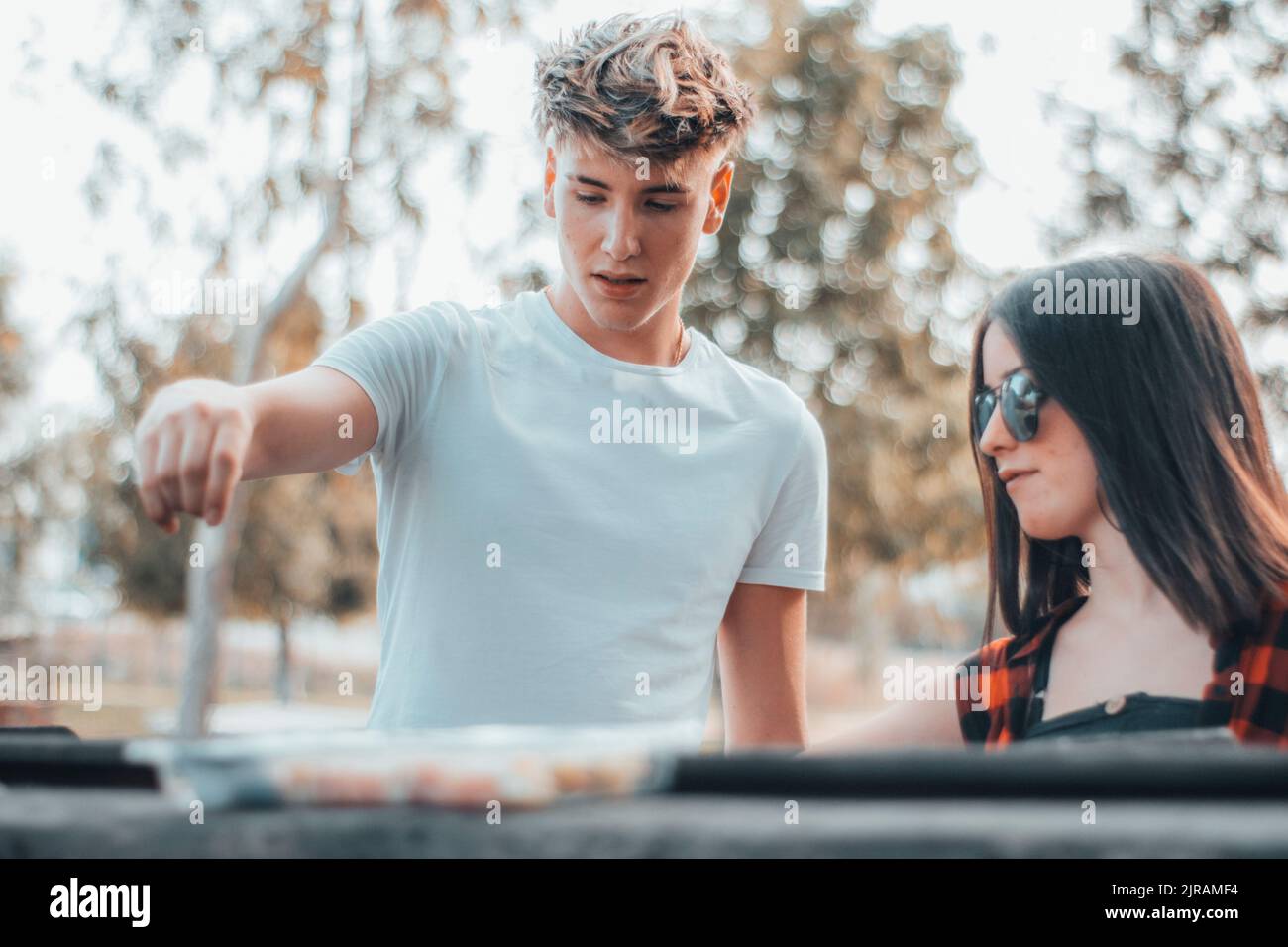 Two young Spanish friends spending time together while cooking in a ...