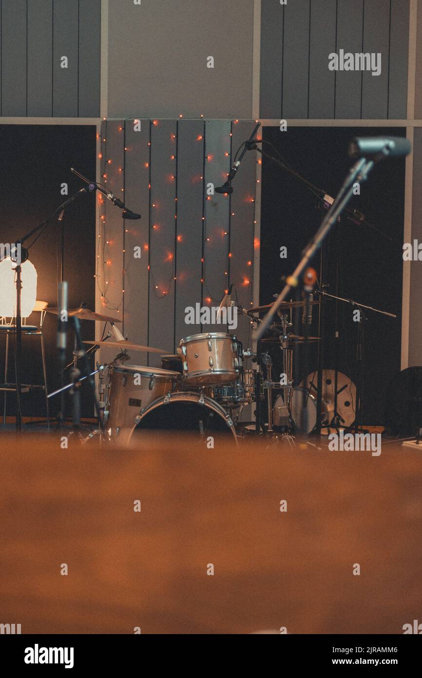 A vertical shot of a recording studio with a drum kit and red lights in ...