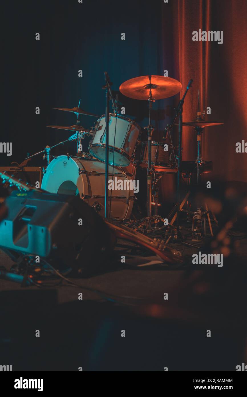 A vertical shot of a recording studio with a drum kit and red lightin ...