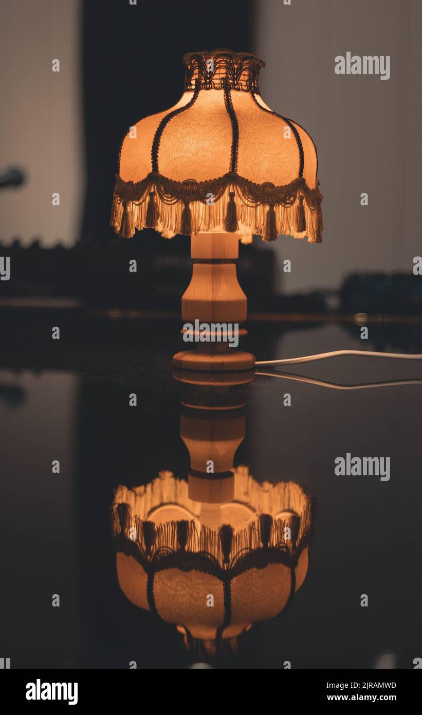 A vertical shot of a reflection of a switched lamp with a lampshade on ...