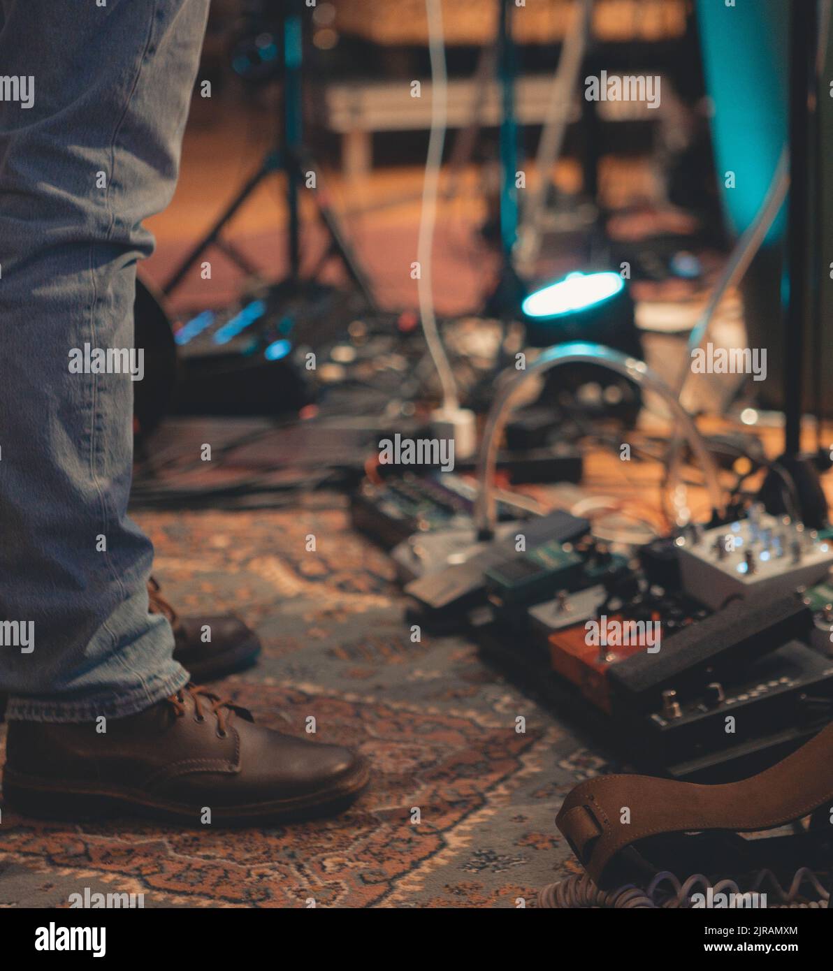 A closeup of musical instruments on the floor and a male's feet ...
