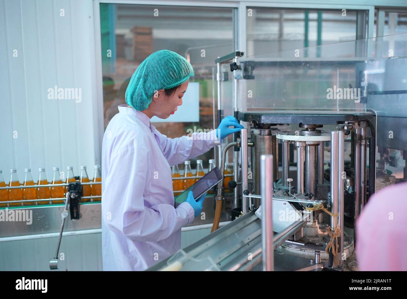 worker controlling the work of machine in production line at beverage ...