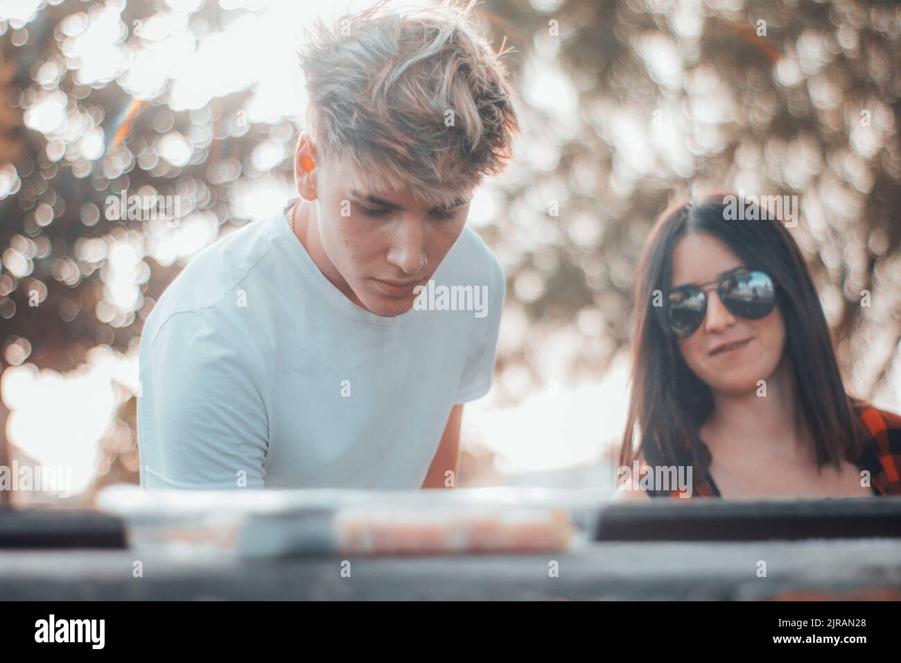 Two young Spanish friends spending time together while cooking in a ...