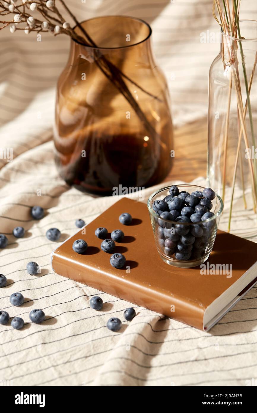 cup of blueberry, book and dried flowers in vases Stock Photo - Alamy