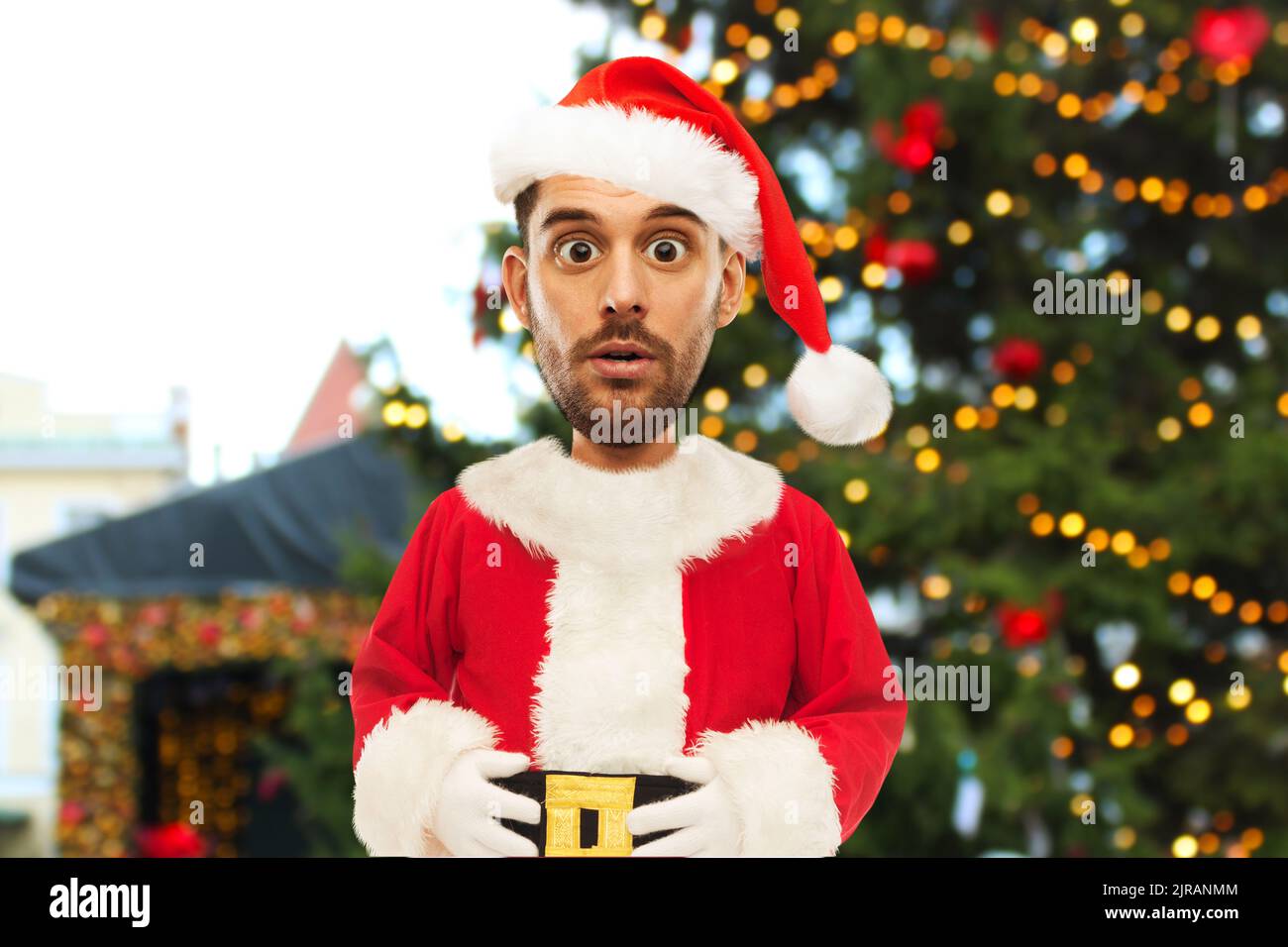 surprised man in santa costume over christmas tree Stock Photo - Alamy