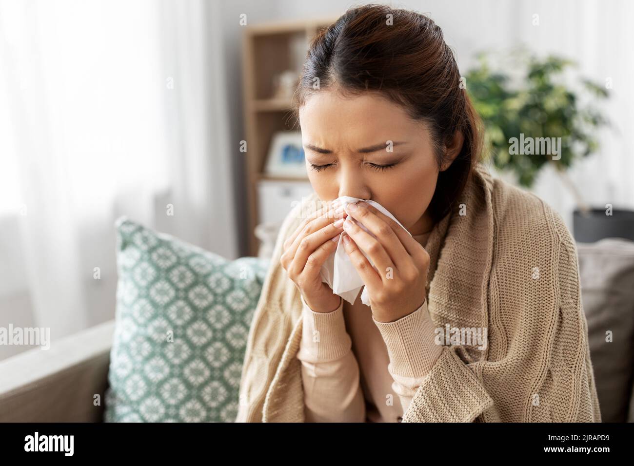 sick woman blowing nose in paper tissue at home Stock Photo - Alamy