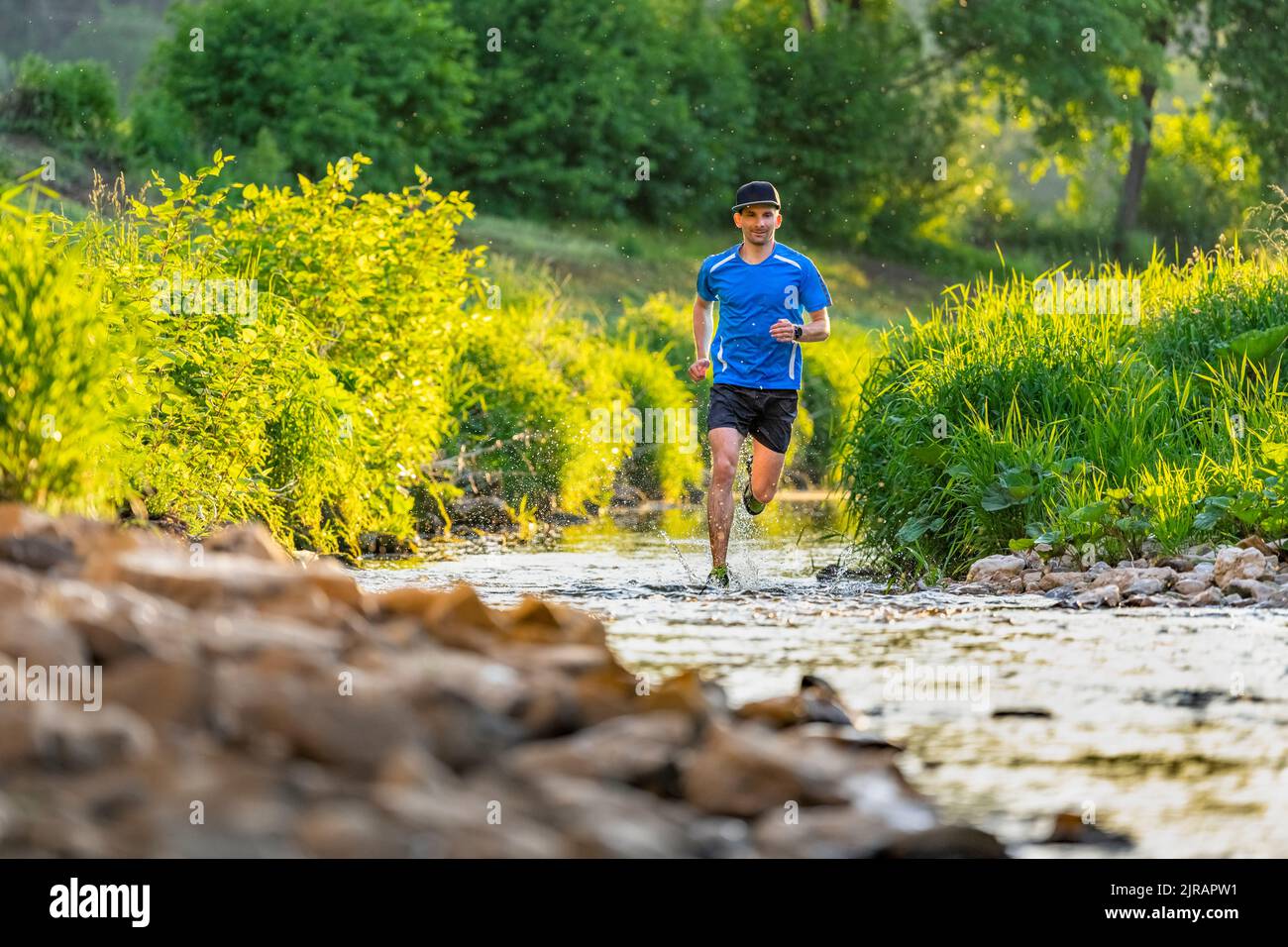 Young man jogging through river Stock Photo - Alamy