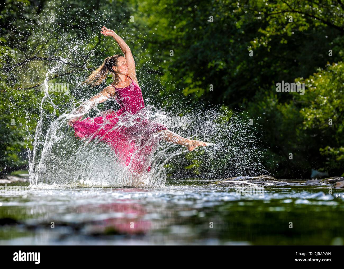 Young woman wearing dress splashing water in river Stock Photo - Alamy