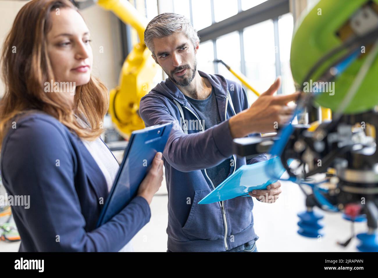 Technicians discussing technical solutions looking at industrial robot ...