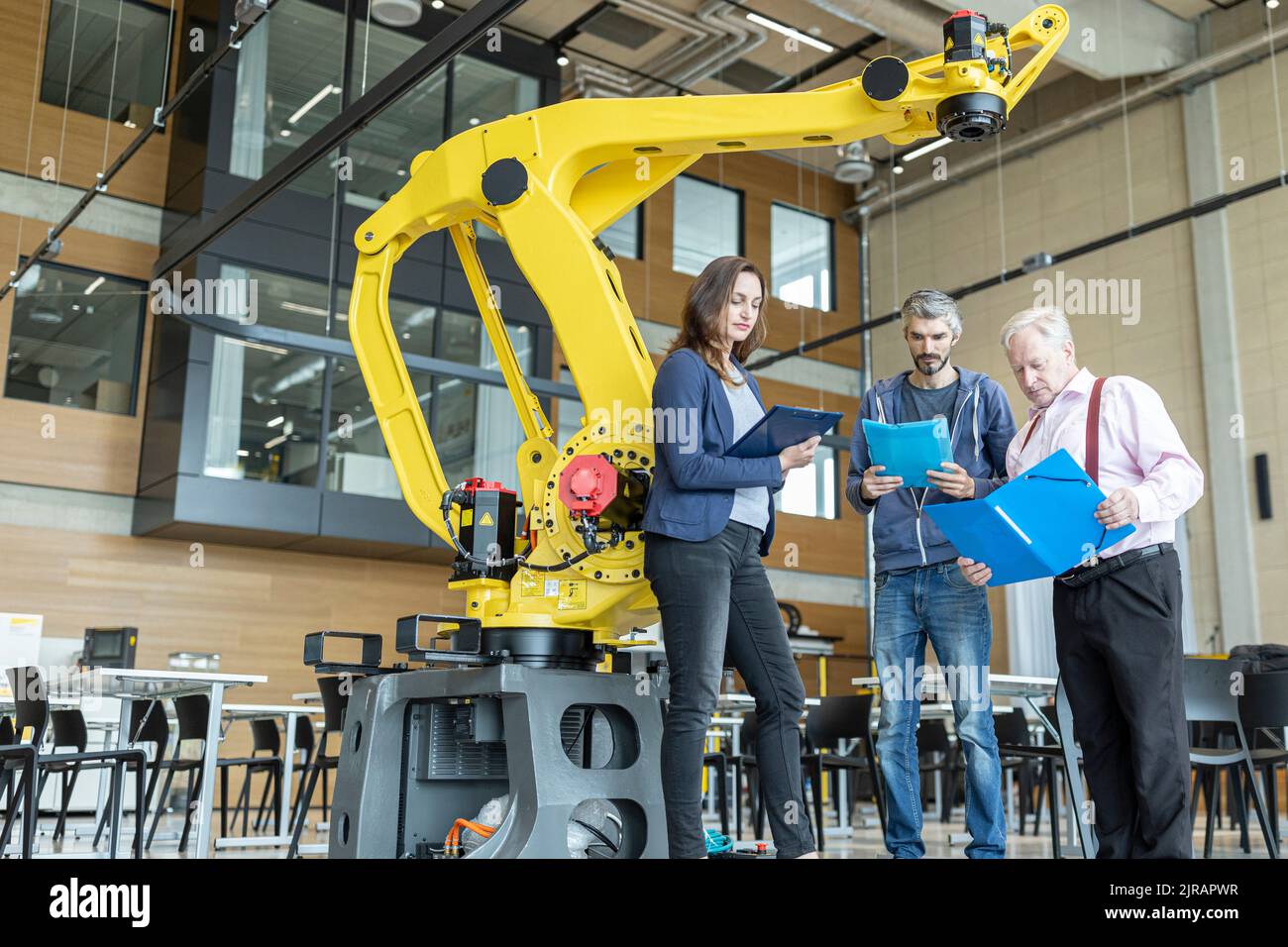 Engineers in factory having meeting in front of industrial robot Stock Photo - Alamy