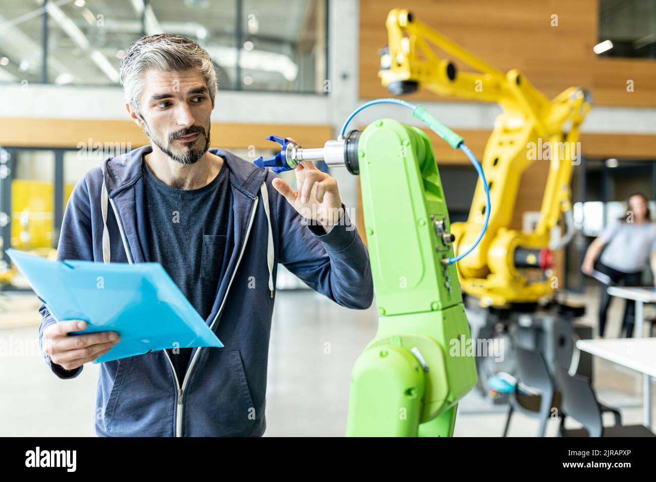 Technician inspecting industrial robot in factory Stock Photo - Alamy
