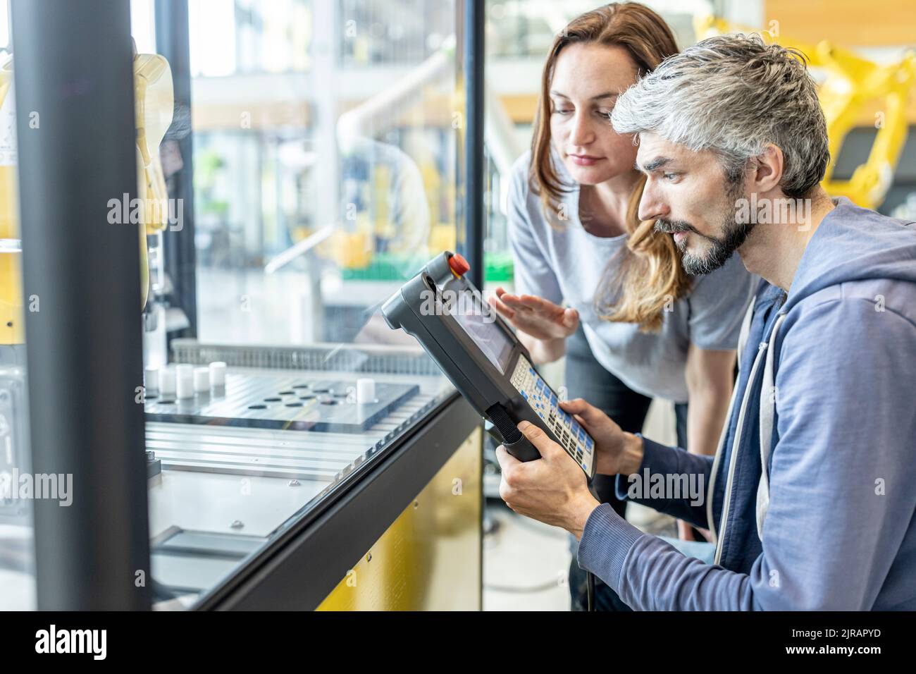 Engineers testing industrial robot in glass cabin Stock Photo - Alamy
