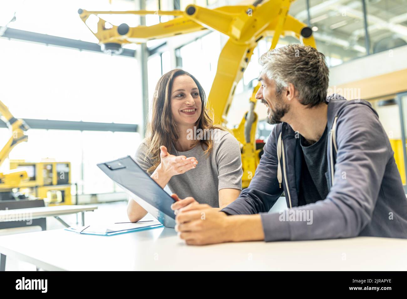 Technician and engineer sitting in factory discussing work solutions ...