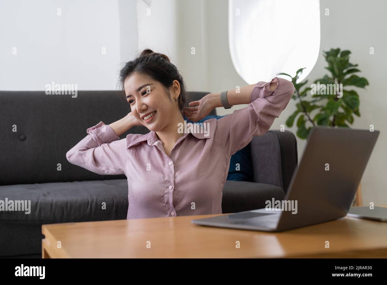 A business woman working in an office stretches to relax from work ...