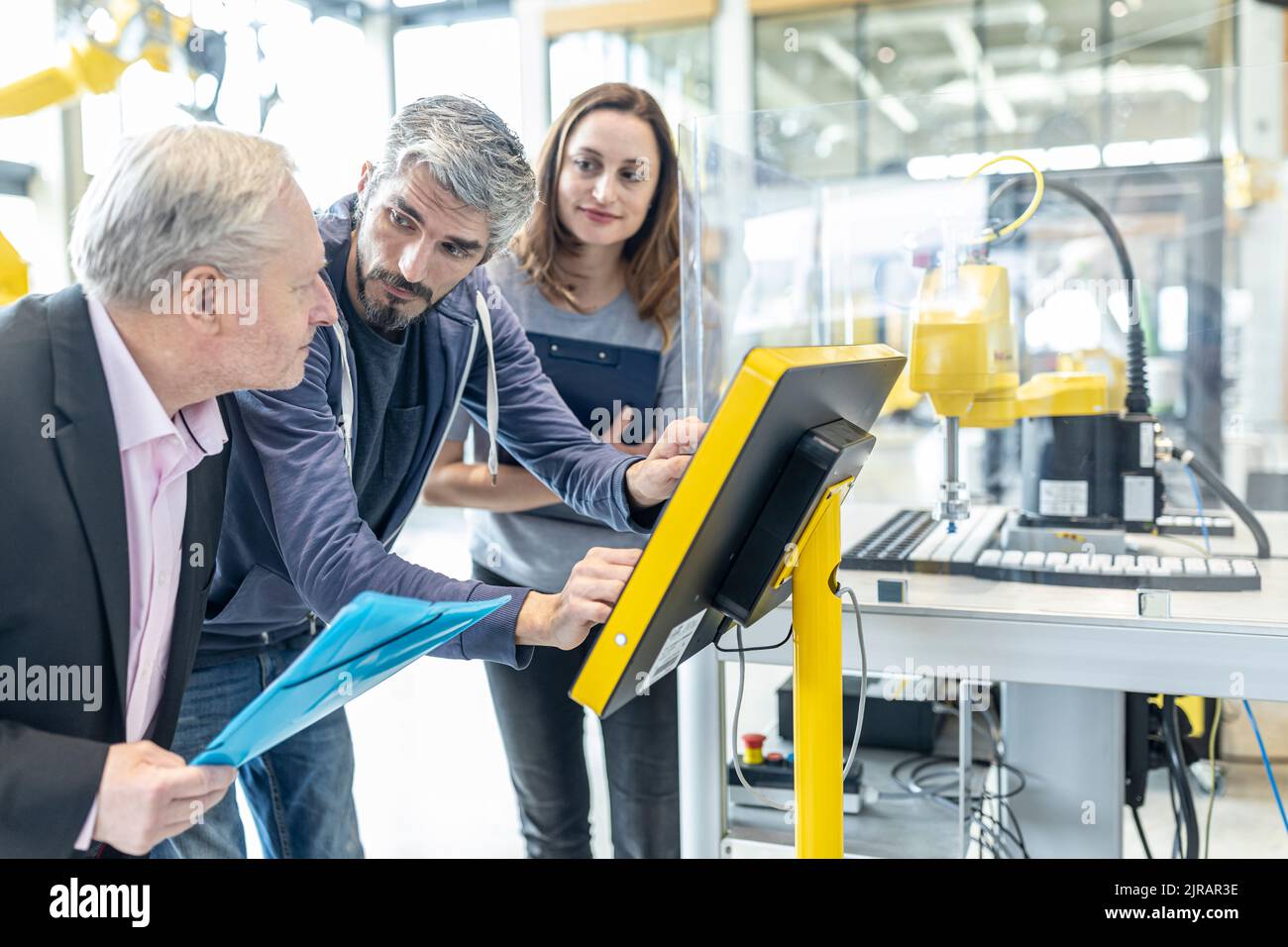 Technicians in industrail factory explaining control panel to senior ...