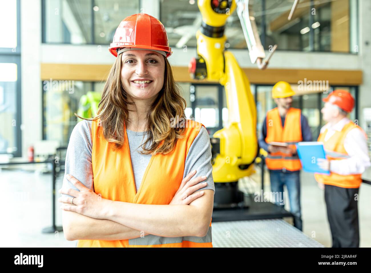 Confident industrial worker standing in robotic factory with arms ...