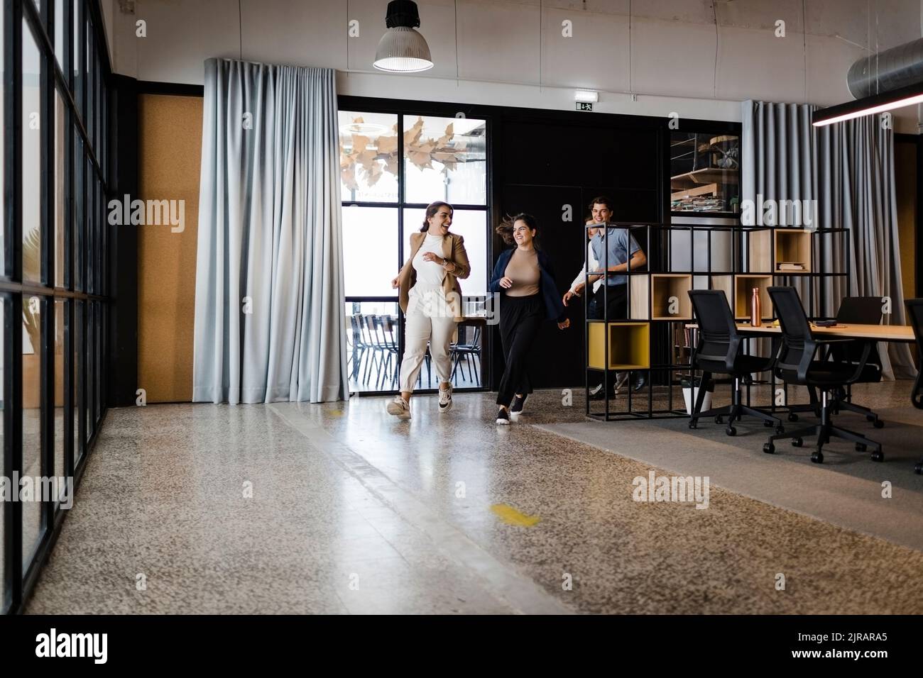 Business colleagues running together in office Stock Photo - Alamy