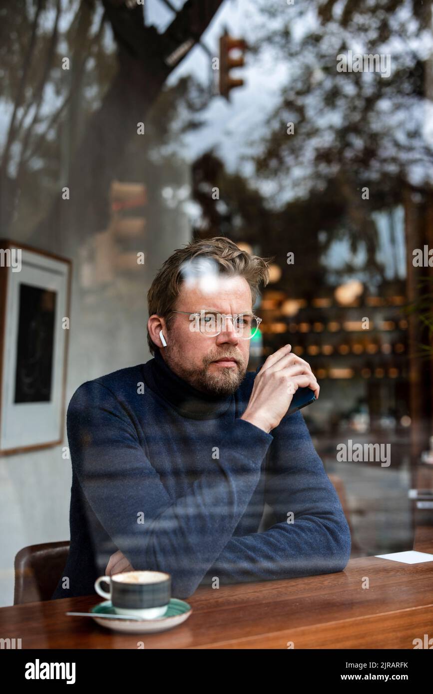 Thoughtful mature businessman in cafe seen through glass window Stock ...