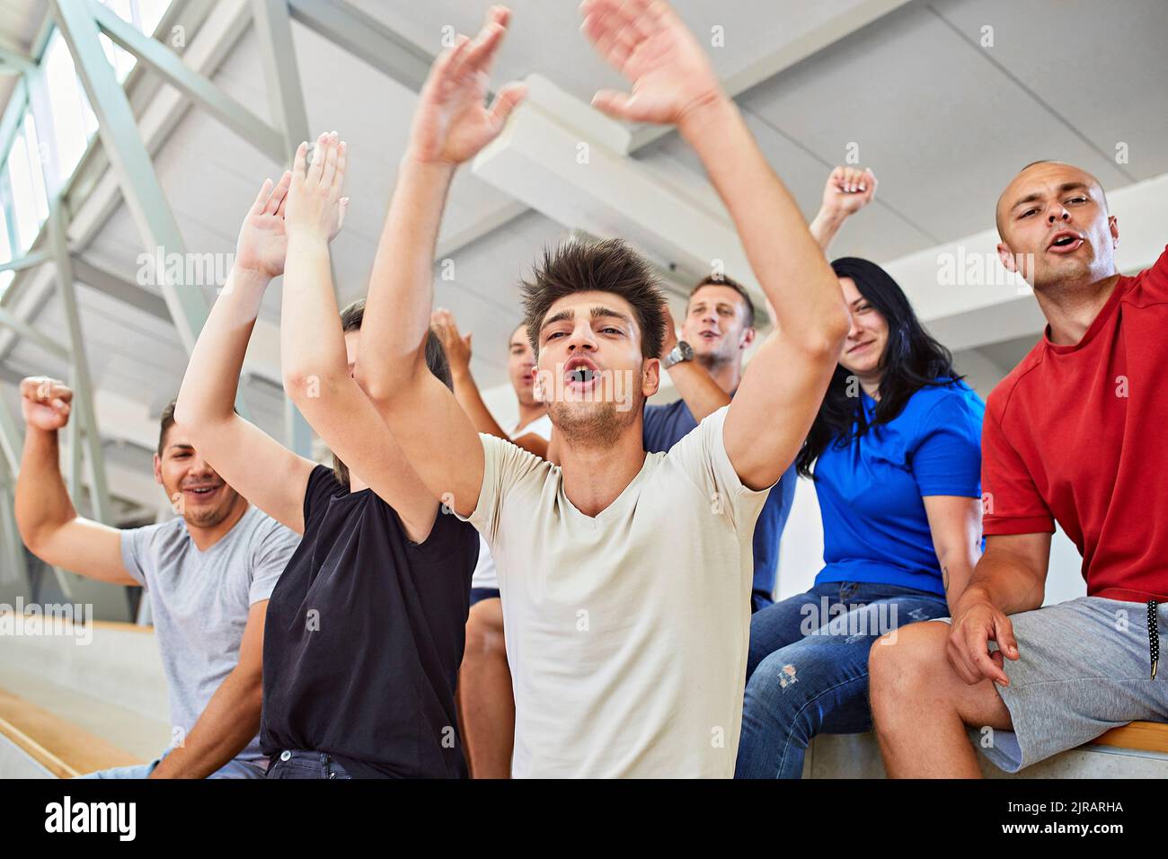 Man with arms raised cheering with friends in stadium Stock Photo - Alamy