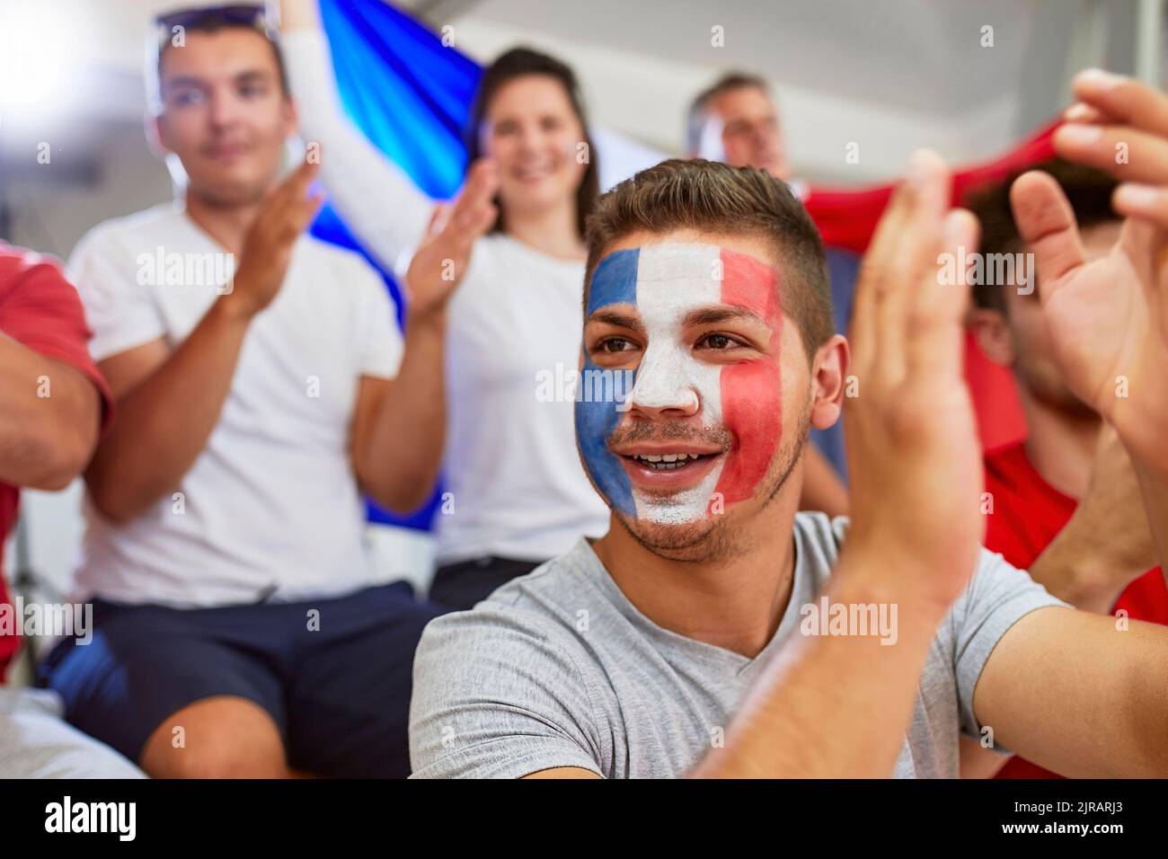 Contemplative man with French Flag painted on face clapping with fans ...