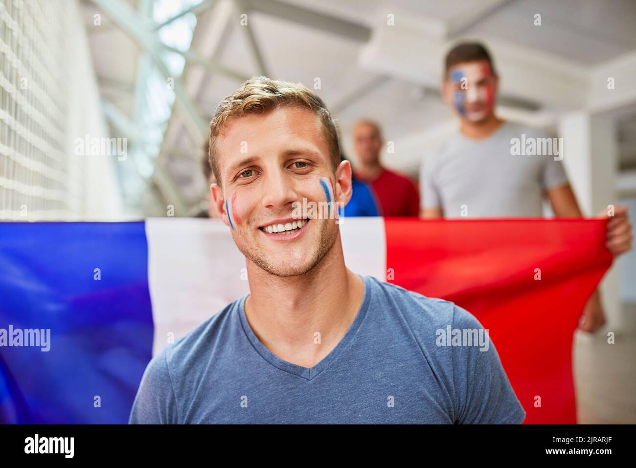 Smiling man with French Flag painted on face at sports event in stadium ...