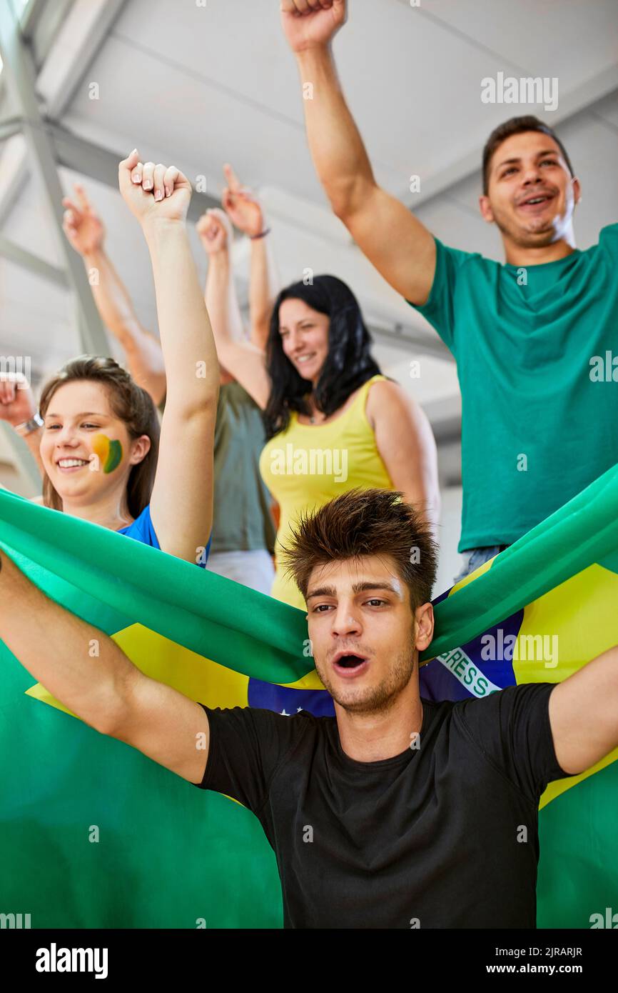 Excited fans with Brazil Flag cheering together at sports event in ...