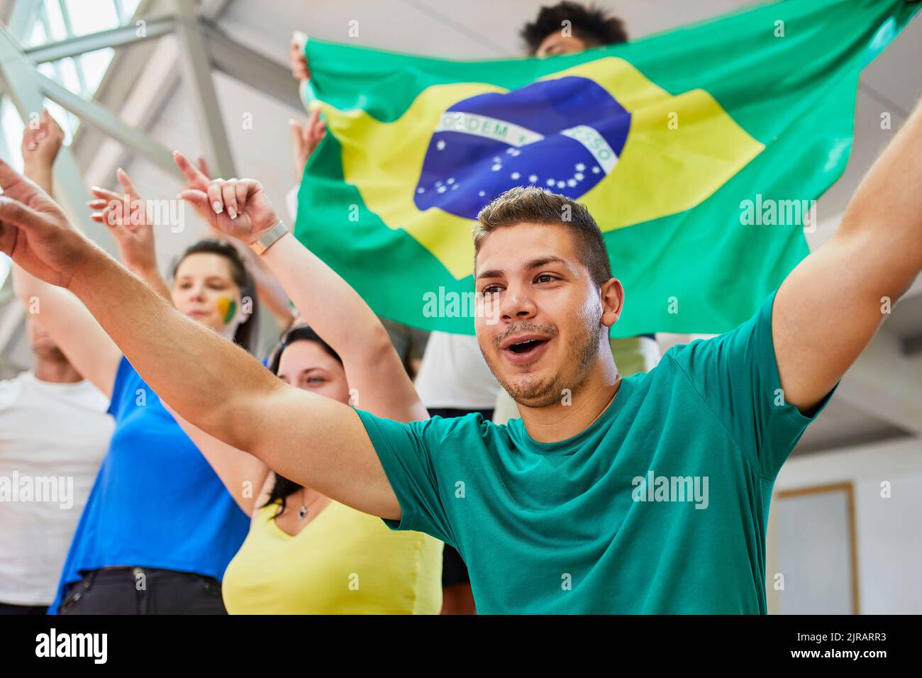 Man with arms raised cheering with fans at sports event in stadium ...