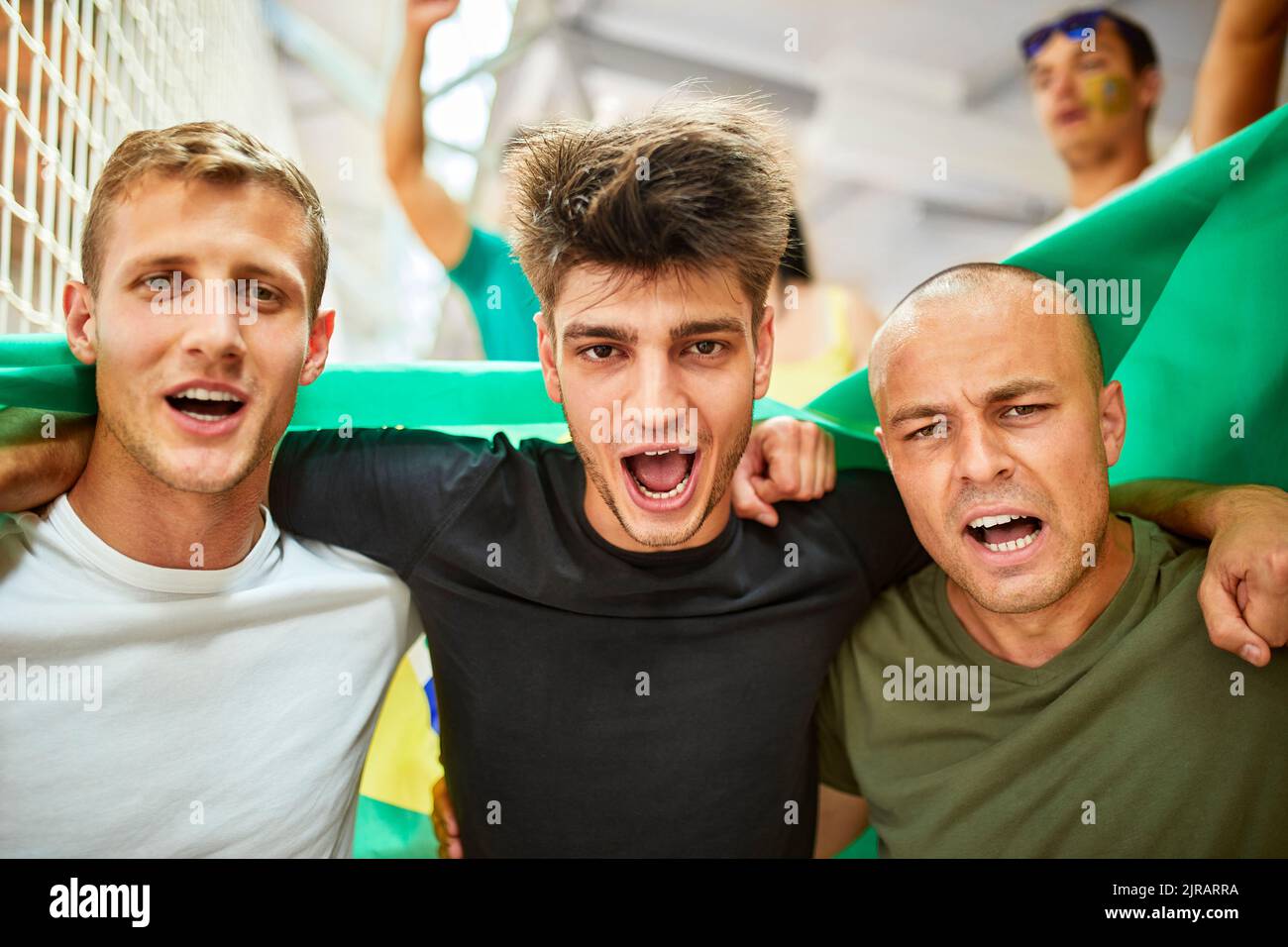 Excited fans with arm around cheering with Brazil Flag at sports event ...