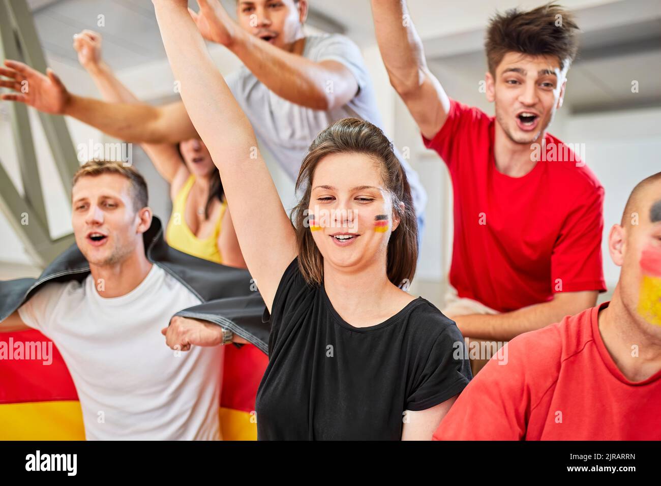 Happy fans with hands raised cheering together at stadium Stock Photo ...