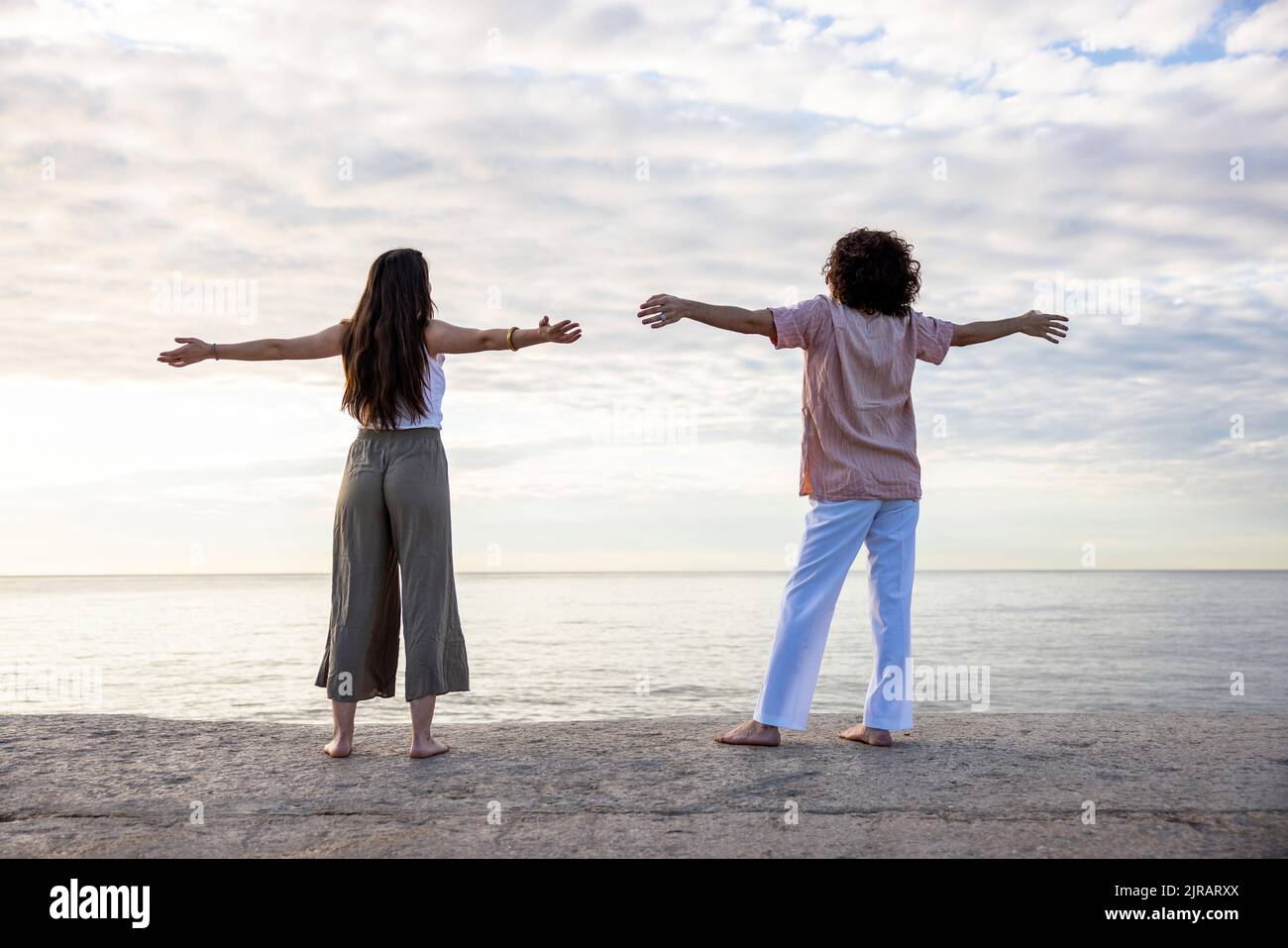 Couple with arms outstretched standing at pier Stock Photo - Alamy