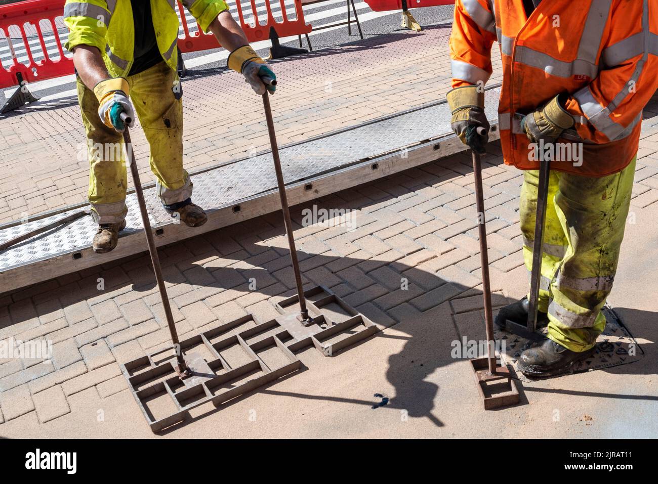 Workers using forming tools on asphalt to create the impression of ...