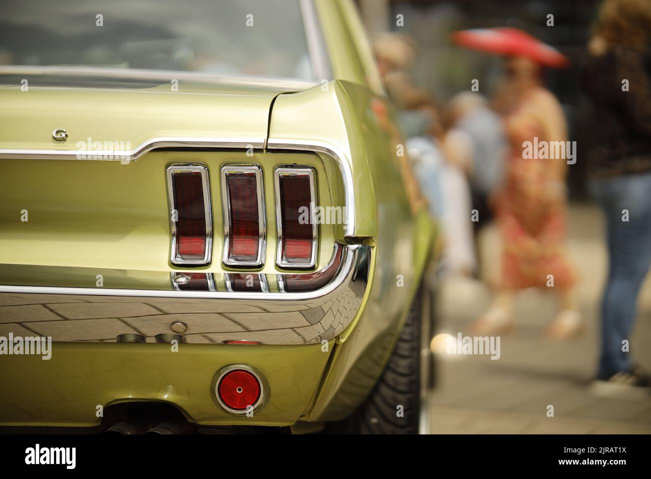A green-toned vintage car on the street during a car show against a ...