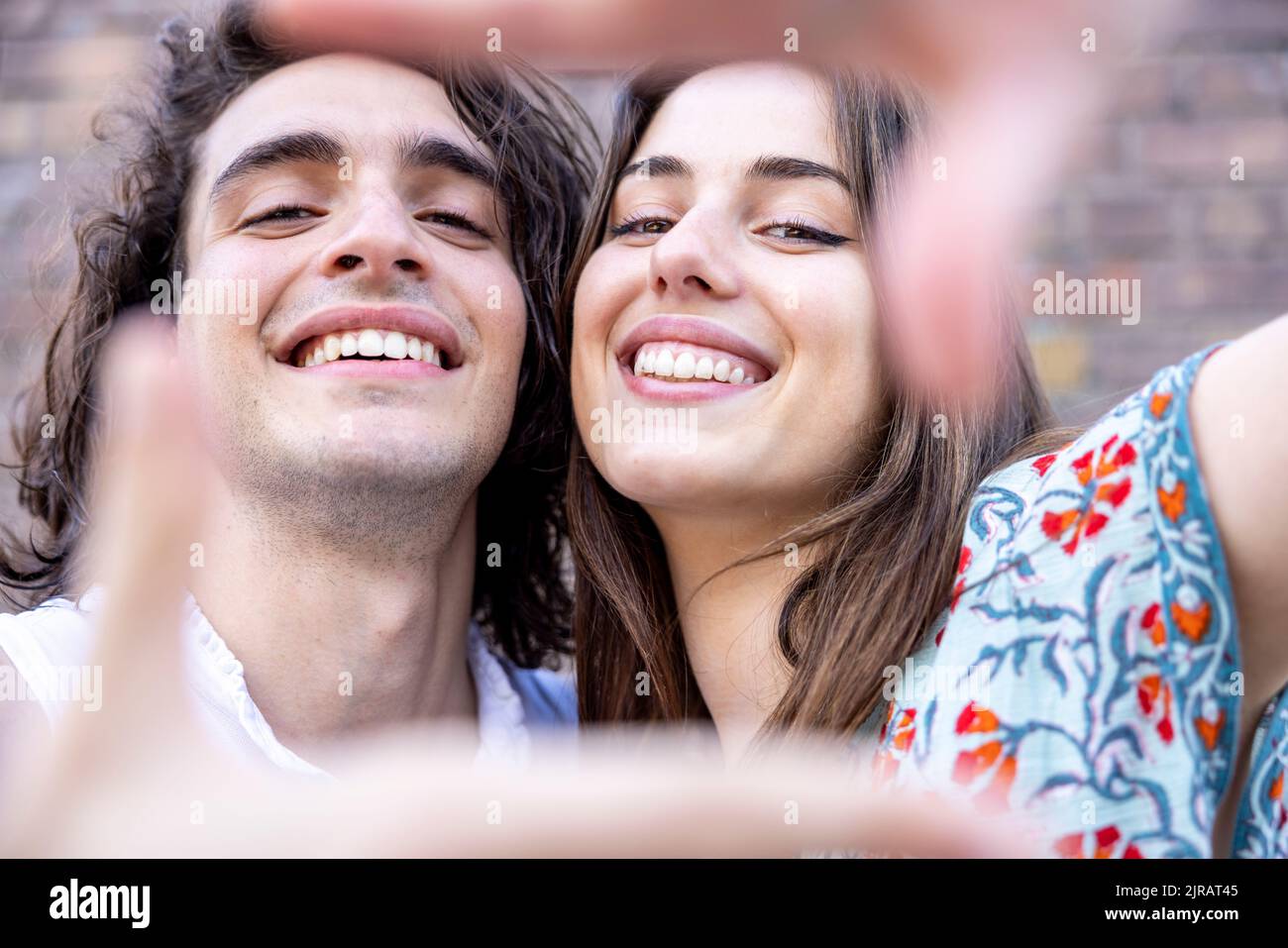 Happy young couple making finger frame with hands Stock Photo - Alamy
