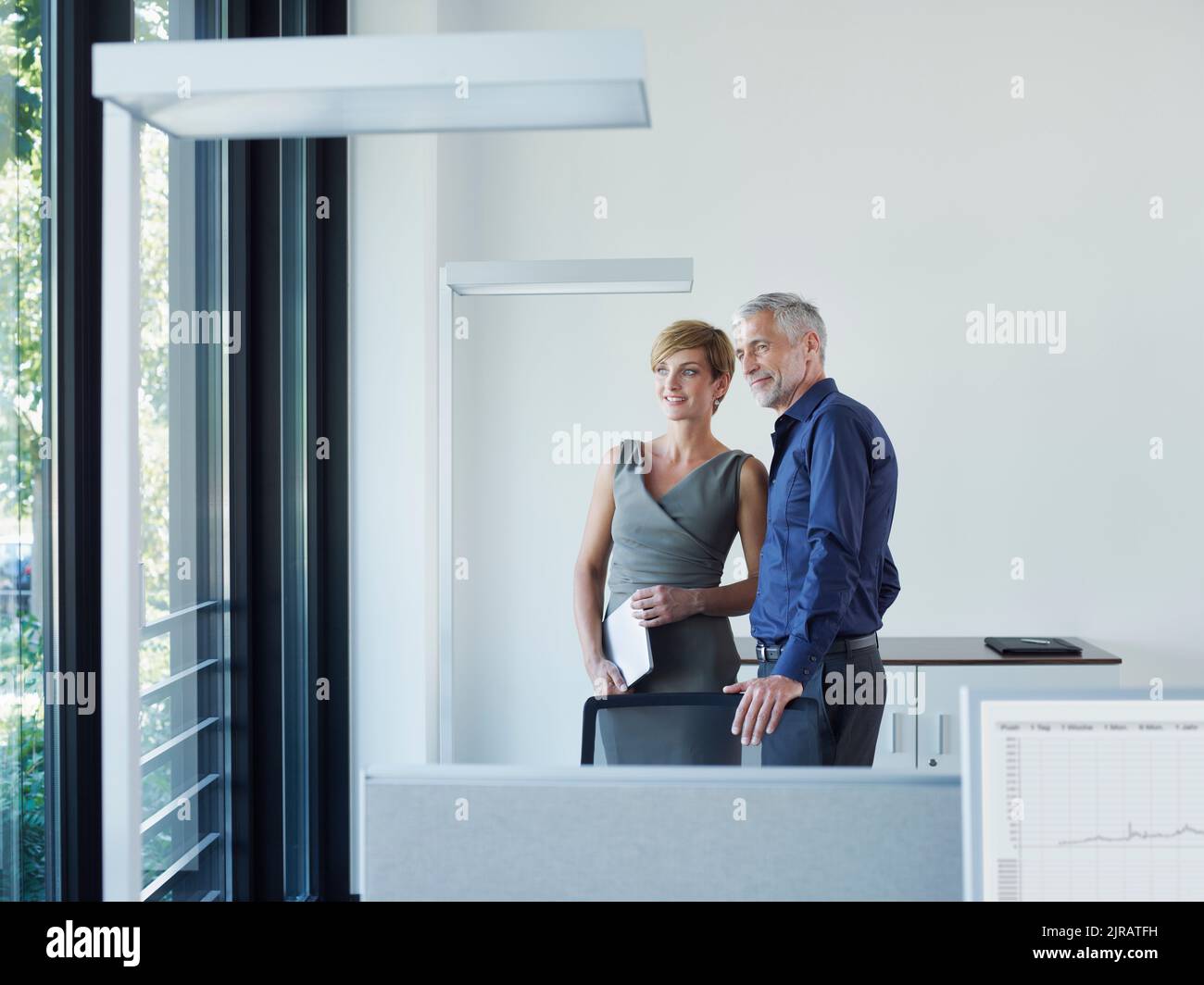 Thoughtful business colleagues looking out through window at office ...