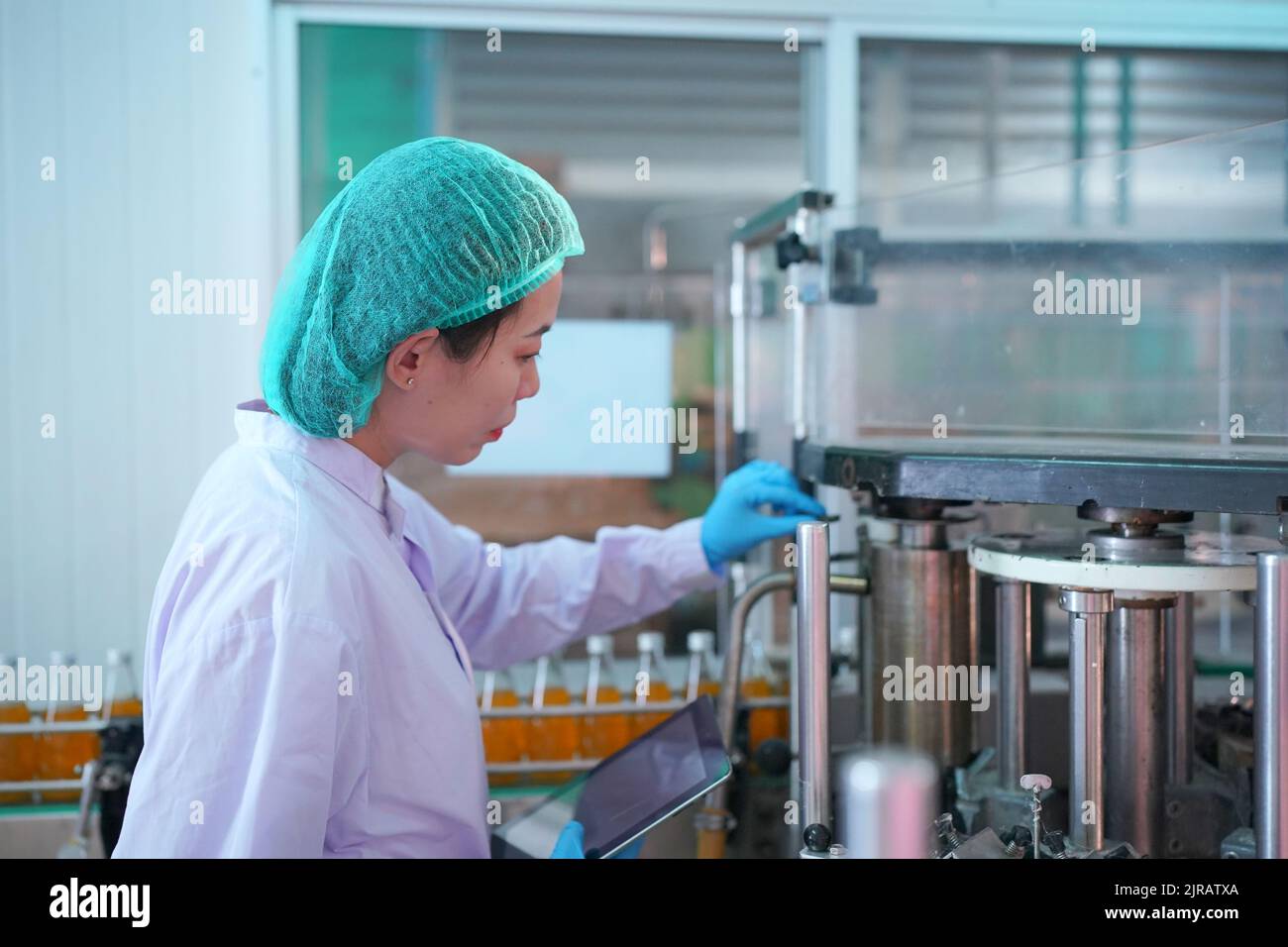 worker controlling the work of machine in production line at beverage ...