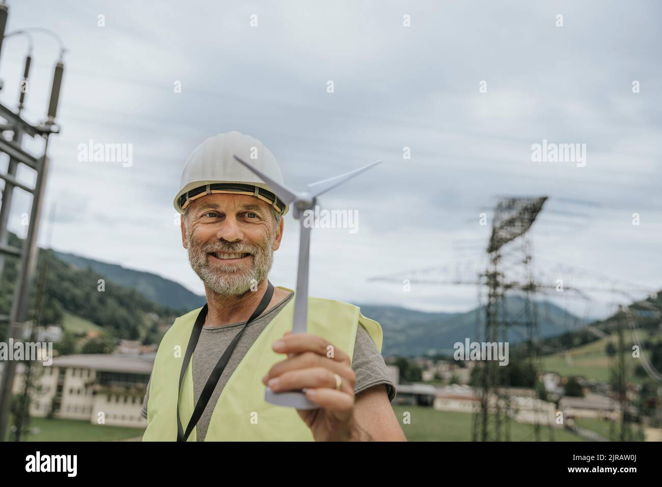Mature engineer holding wind turbine model at power station Stock Photo ...