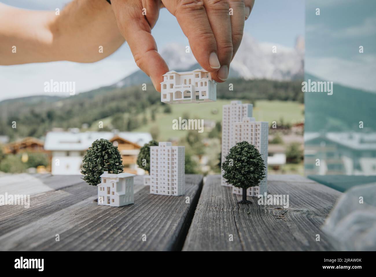 Hand of engineer positioning model home on table Stock Photo - Alamy