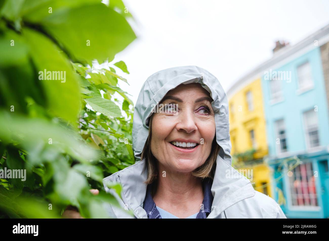 Smiling senior woman wearing windbreaker by plants Stock Photo - Alamy
