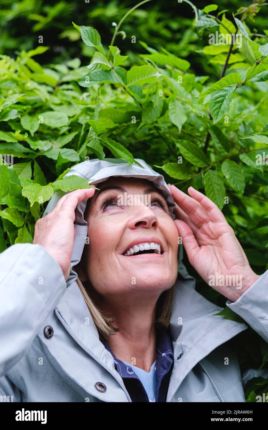 Smiling woman wearing windbreaker in front of leaves Stock Photo - Alamy