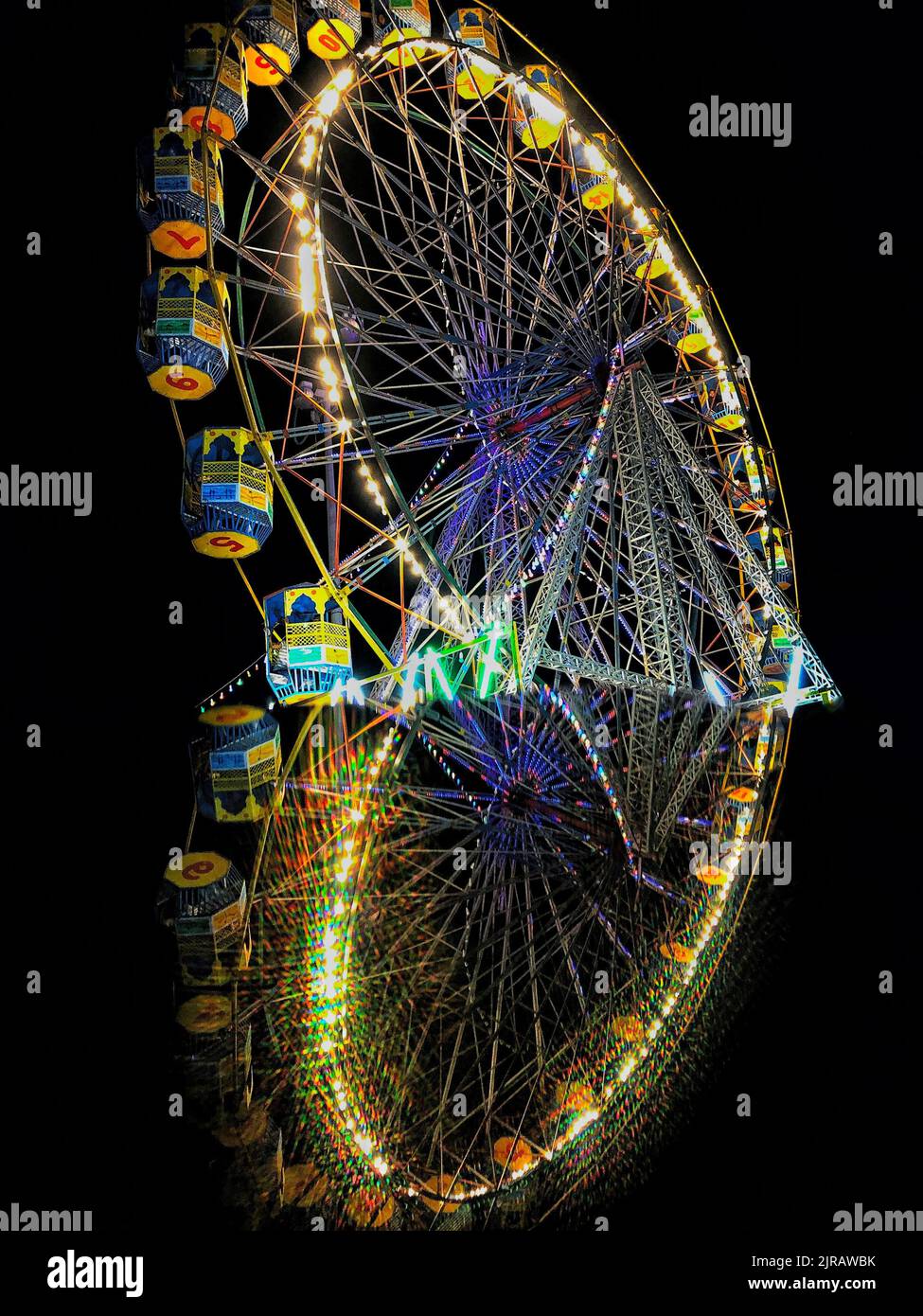 A vertical shot of an illuminated Ferris Wheel with a reflection Stock ...