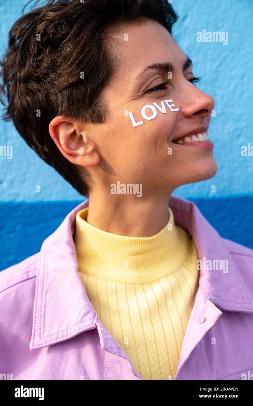 Smiling woman with love text on cheek Stock Photo - Alamy